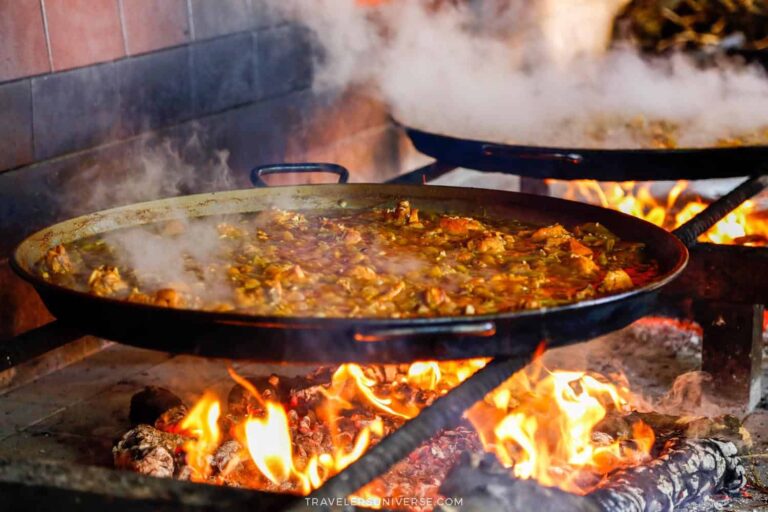 A large pan of paella, the most iconic food in Valencia, being cooked over an open fire
