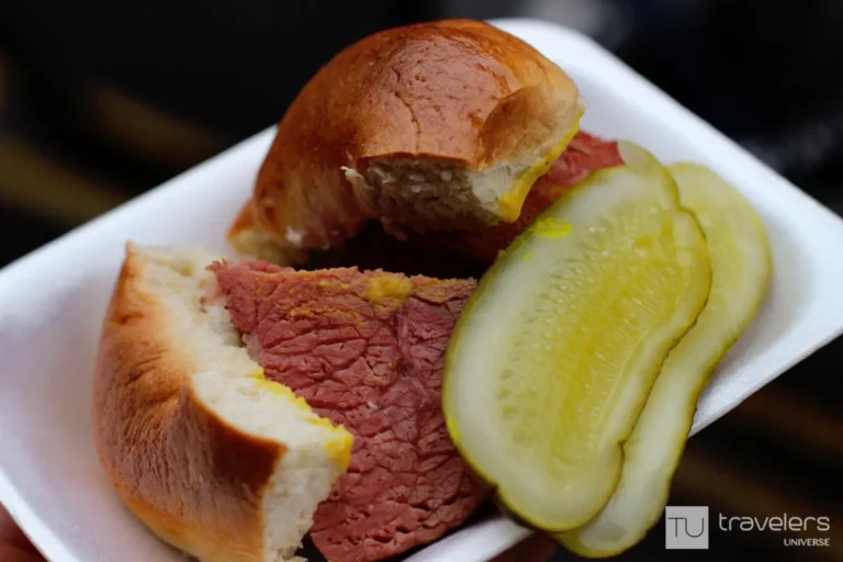 Salt beef bagel with pickles on a disposable plate