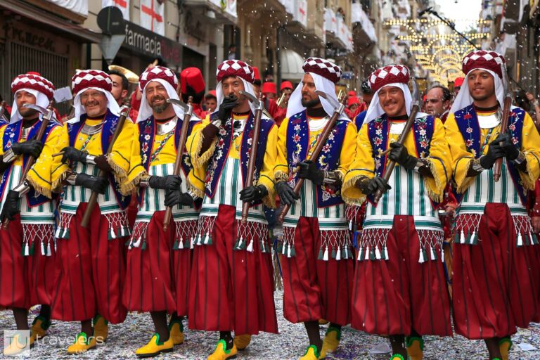 A row of people dressed in colorful Moorish clothes at a Moros y Cristianos parade in Alcoy