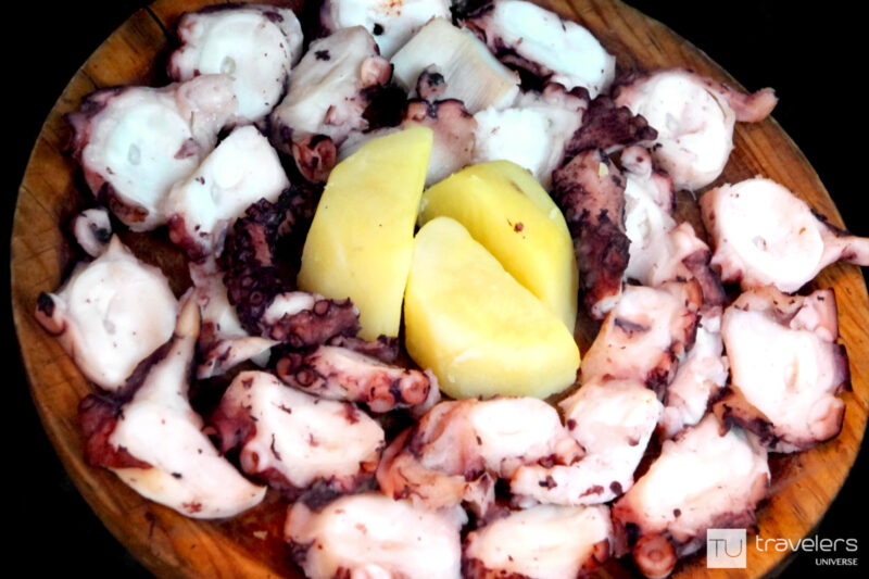 Bite-size chunks of octopus and potatoes on a wooden plate