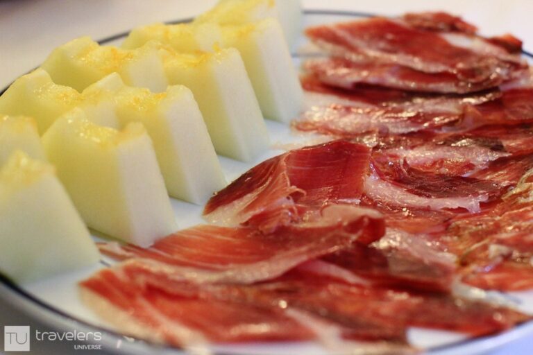Thinly sliced dry-cured ham with melon on a white plate