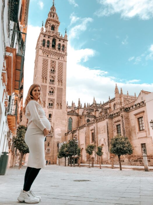 Pregnant Emily posing in front of the Giralda tower while living in Seville