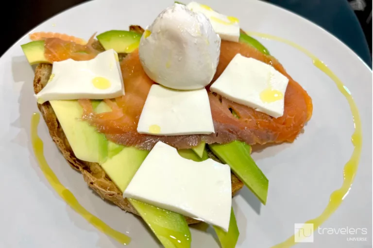 Avocado toast with smoked salmon and cheese on a white plate