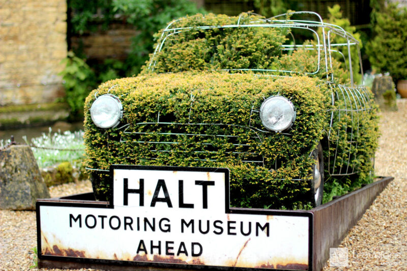 Topiary car with 'Motoring Museum ahead' tin sign