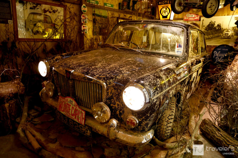 A black car covered in dirt with branches and other exhibits around it at Motoring Museum in Bourton-on-the-Water