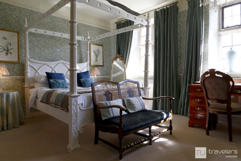 Four poster bed, wooden desk, and green curtains and wallpaper in a room at The Dial House in Bourton on the Water