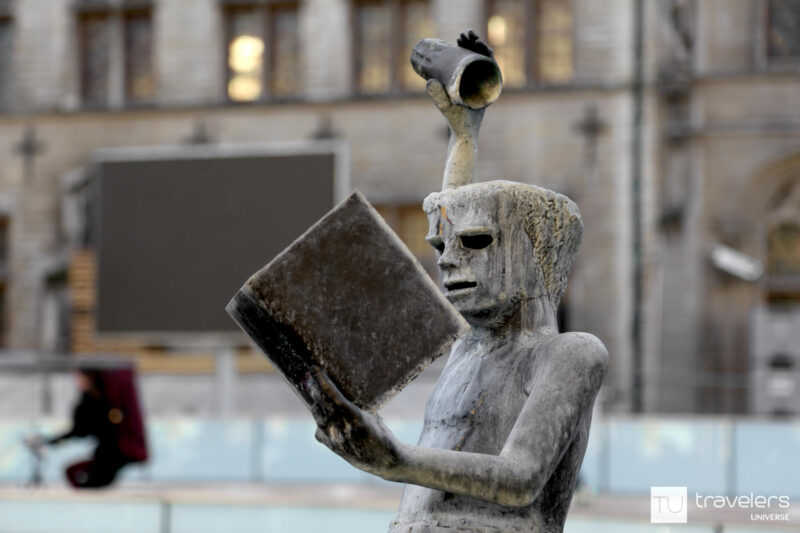 A statue of a guy reading a book and pouring wisdom into his head