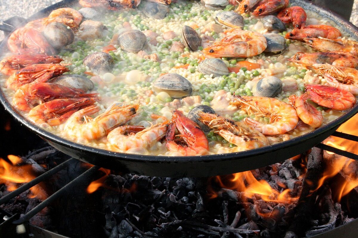 Mixed paella with seafood cooking over a wood fire in the traditional Valencian style