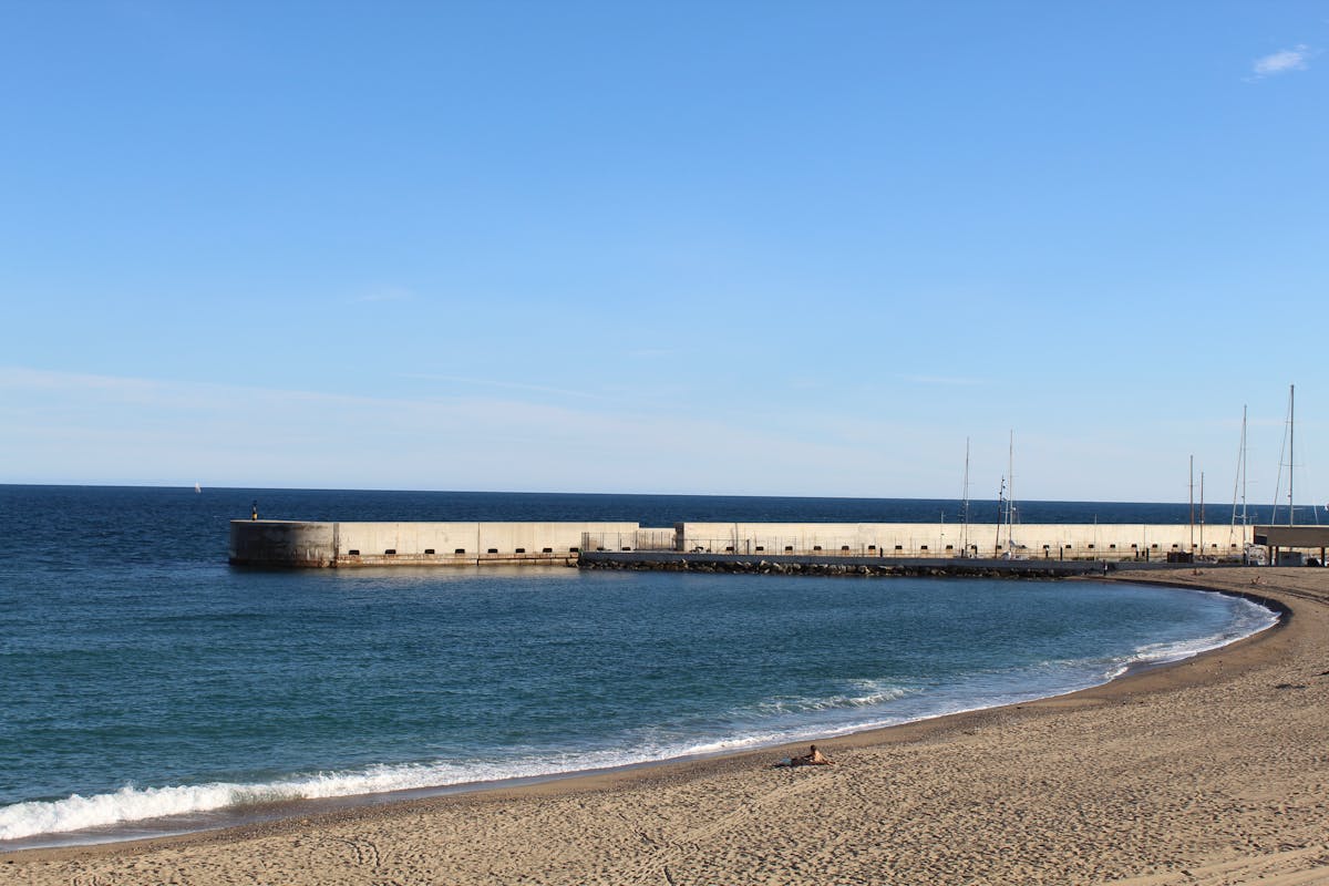Barcelona beach with pier stretching into the blue Mediterranean Sea