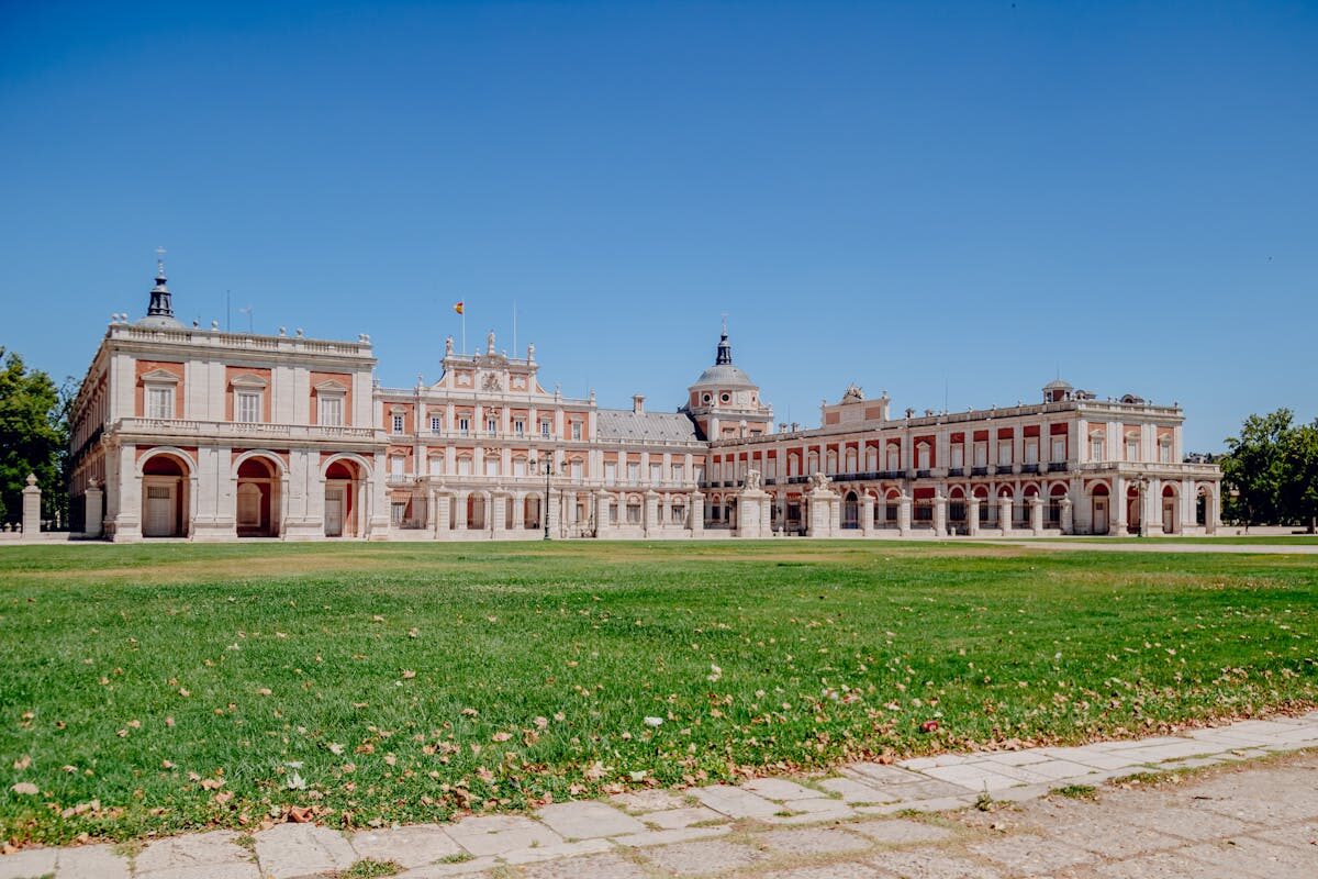 The Royal Palace of Aranjuez surrounded by lush gardens under a blue sky