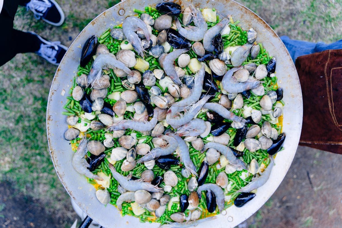 Valencian paella with clams cooking over an open fire