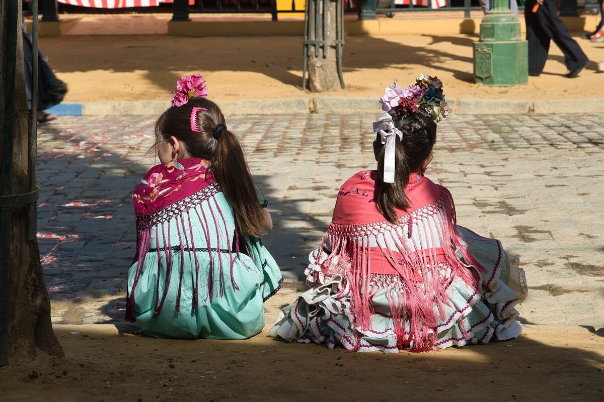 Girls in colorful flamenco dresses sitting during Seville's Feria de Abril