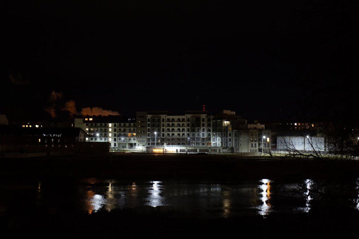 Nighttime cityscape with illuminated buildings reflecting on a river