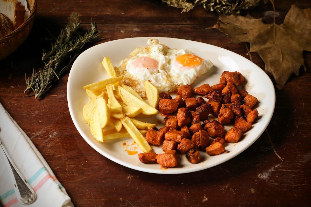 Fried eggs over crispy potatoes and meat on a rustic plate