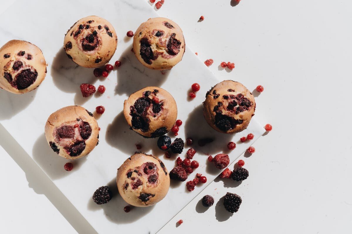 Homemade muffins with fresh berries on a marble surface