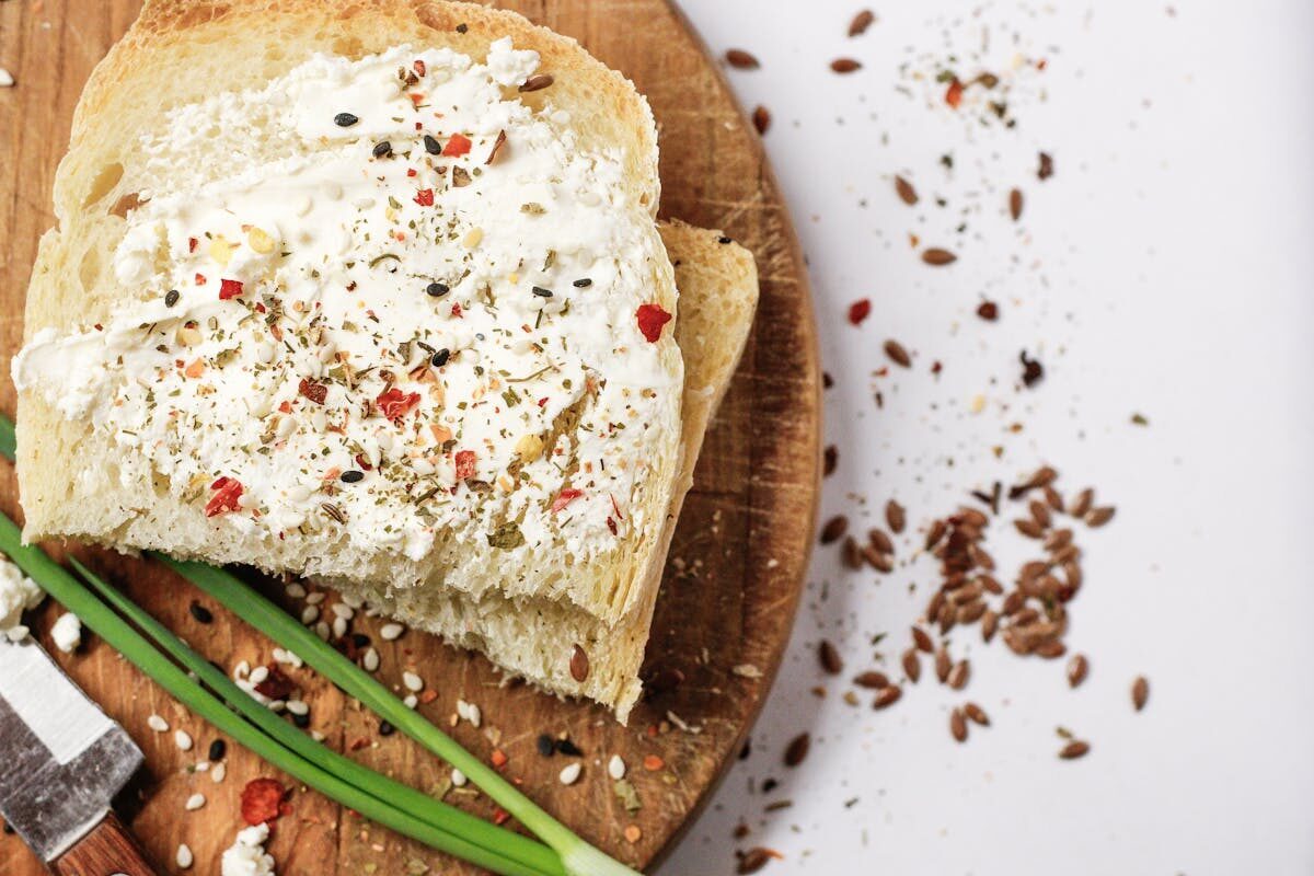 Close-up of bread with a creamy spread and herbs on a wooden board