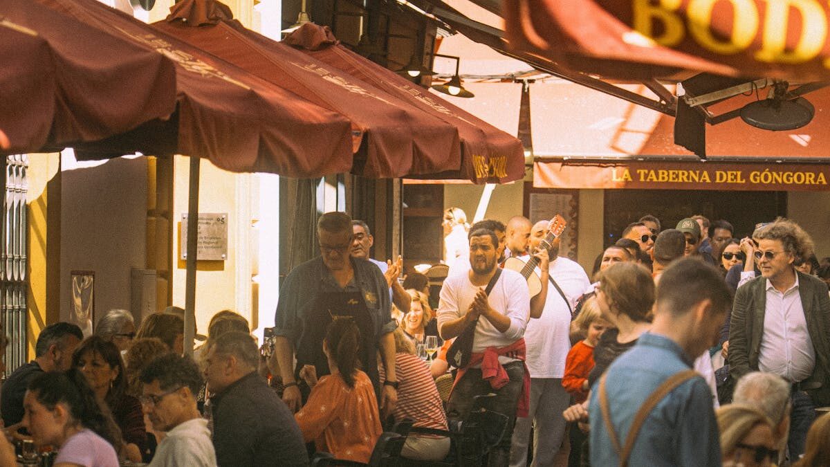 Outdoor dining scene with musicians performing at a traditional taberna in Seville