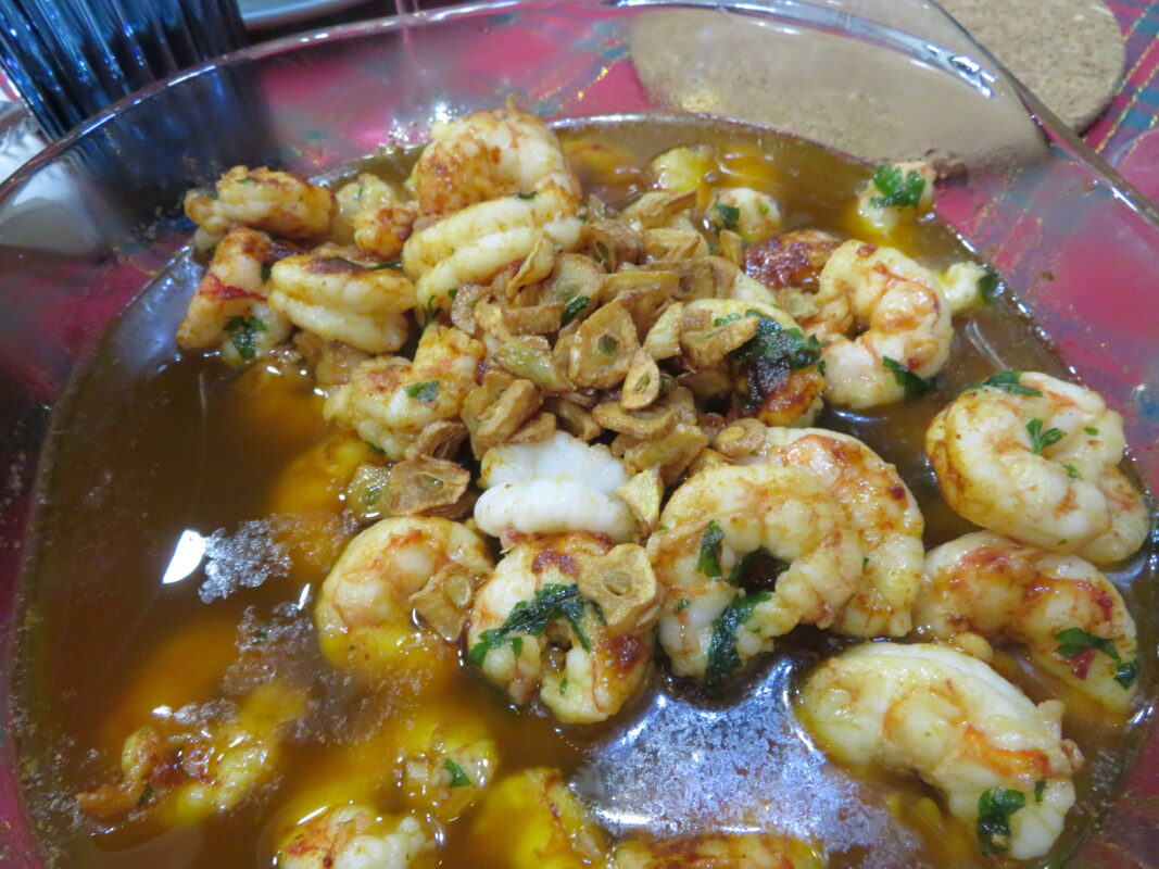Gambas al ajillo sizzling in a clay cazuela