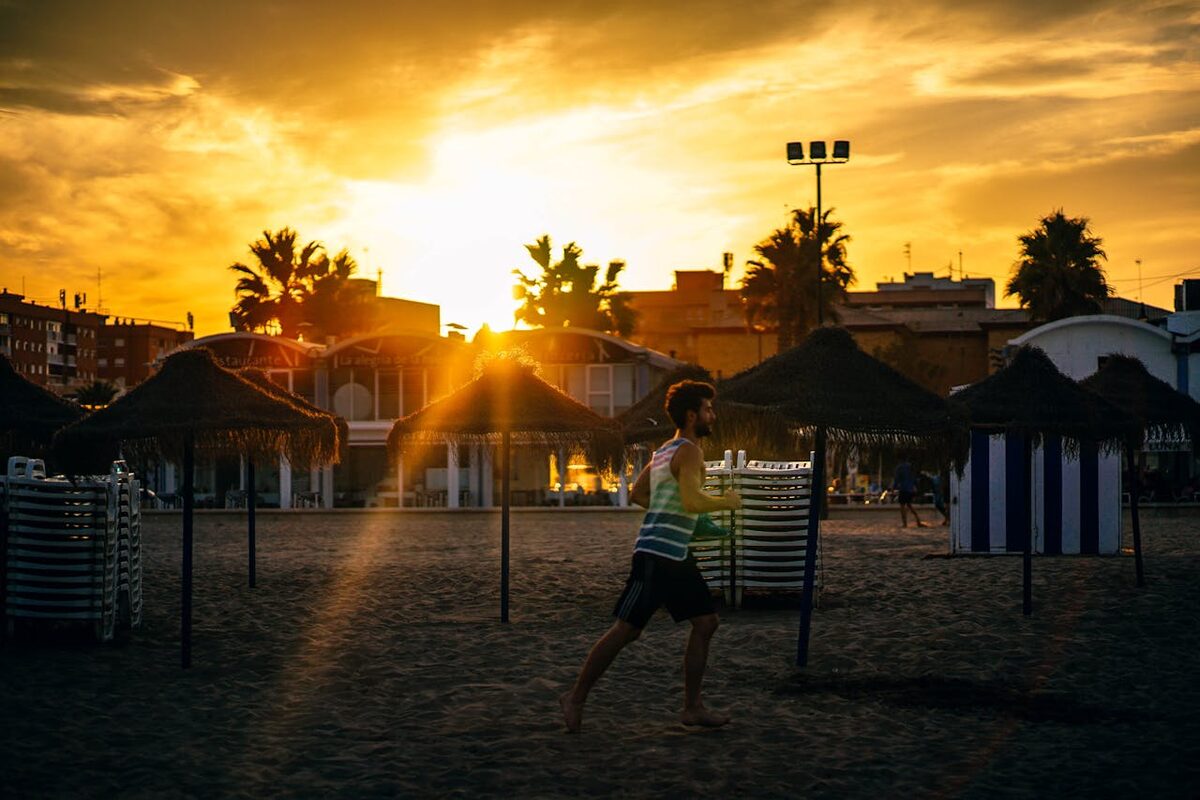 A man jogging along Valencia beach at sunset with warm golden light over the Mediterranean