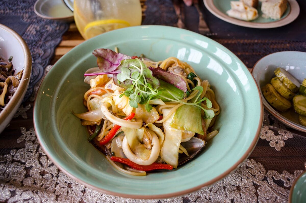 Seafood pasta served with fresh vegetables and herb garnish on a white plate