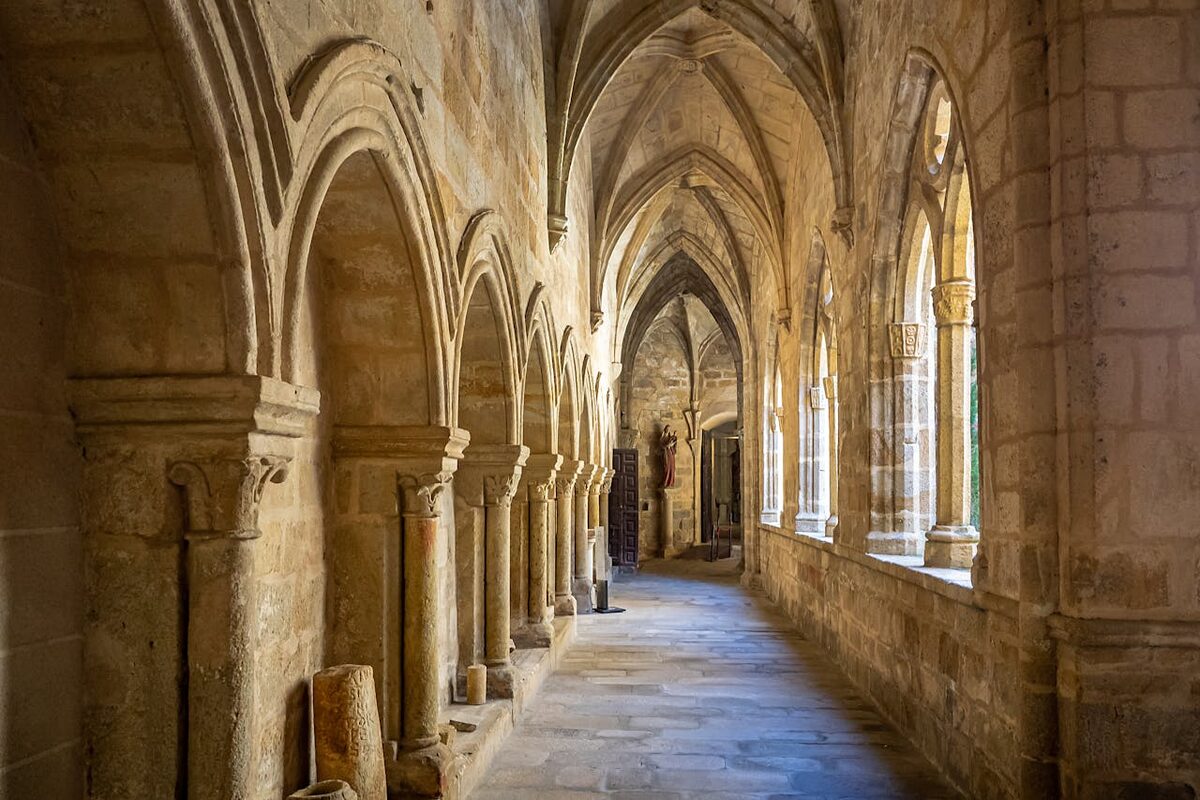 Row of Gothic stone arches lining a corridor in a medieval Spanish building