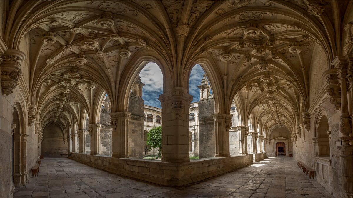 Sunlit cloisters with ornate stone arches in a Renaissance monastery in Spain