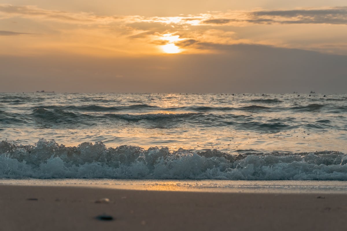 Warm golden hour light washing over Mediterranean waves on a beach near Valencia Spain