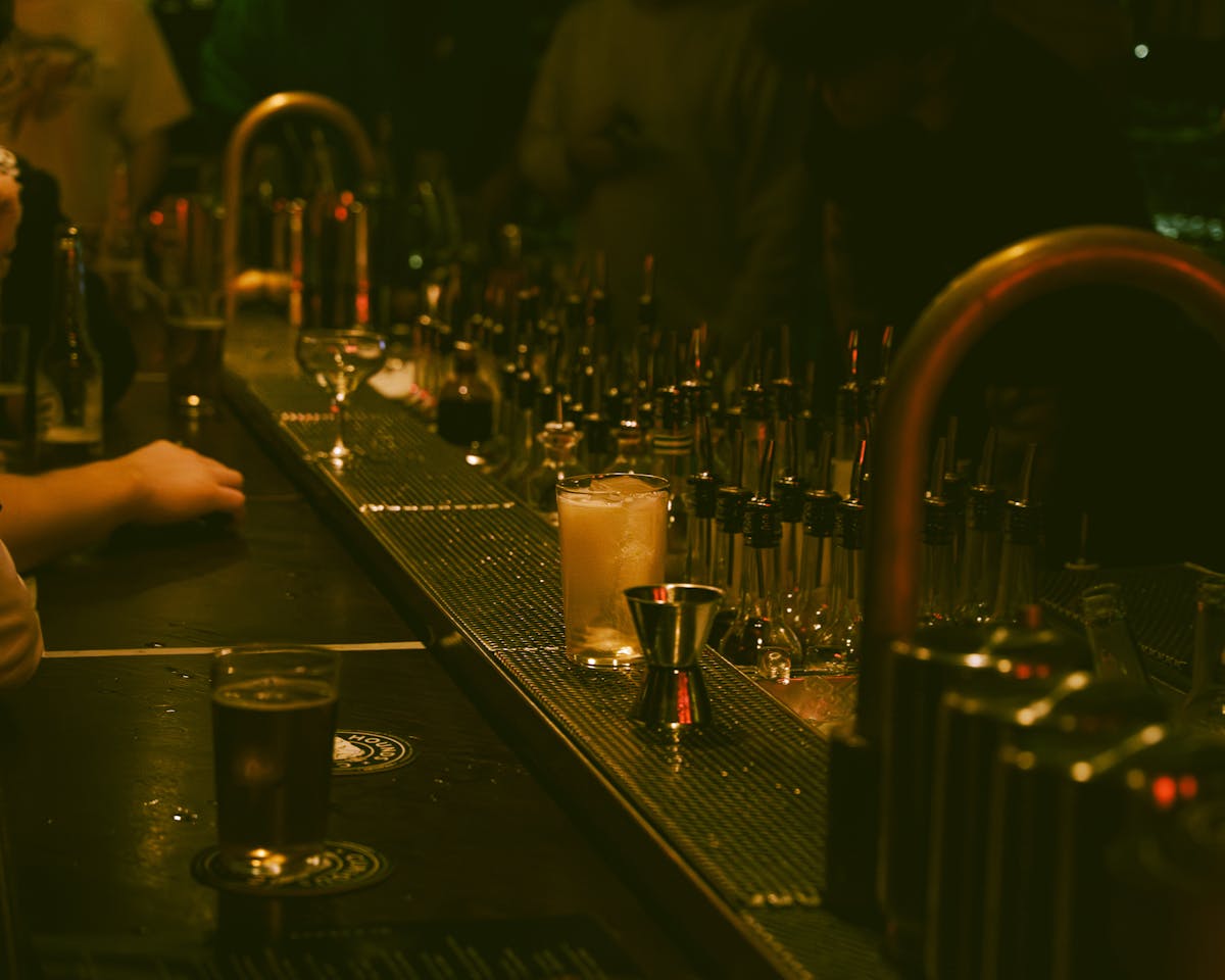 Dimly lit bar with a cocktail and bar tools creating an intimate atmosphere