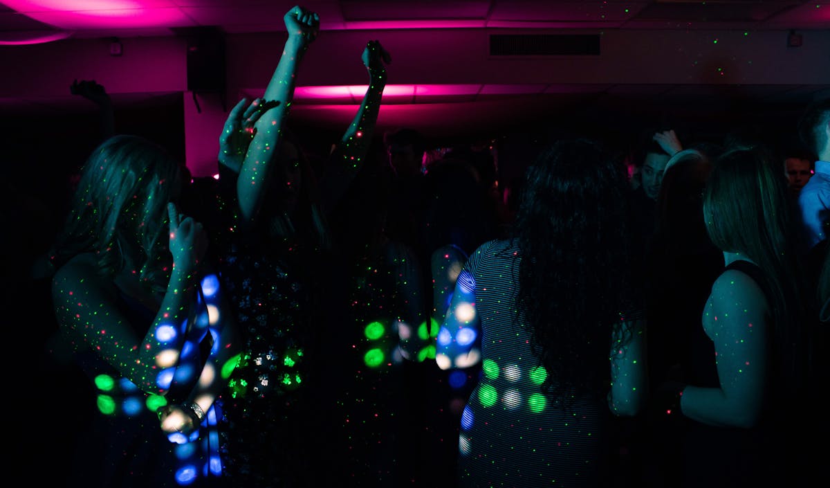 People dancing under colorful neon lights at a nightclub