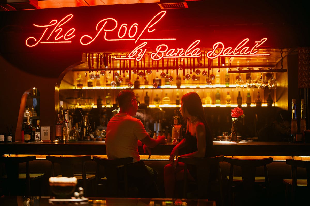 People enjoying evening drinks at a rooftop bar with warm lighting