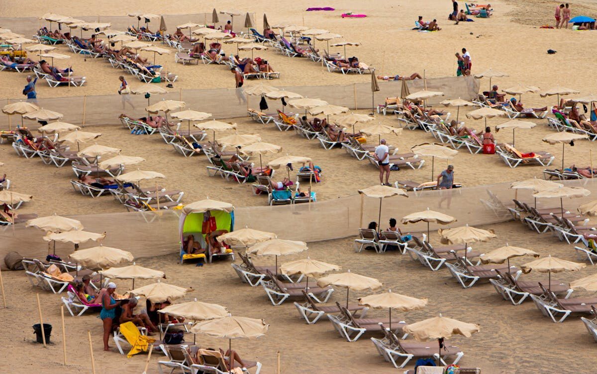 Crowded Mediterranean beach with sun loungers and umbrellas