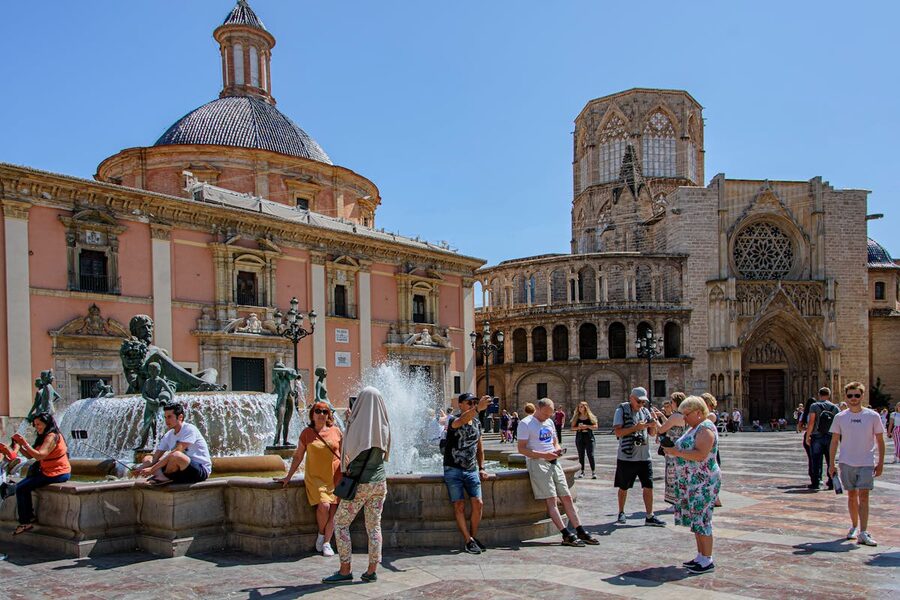 Tourists enjoying Plaza de la Virgen in Valencia with the cathedral in the background