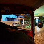 A tuk tuk driving through a colorful Lisbon street