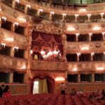 The ornate interior of Teatro La Fenice opera house in Venice showing gilded box seats and the painted ceiling