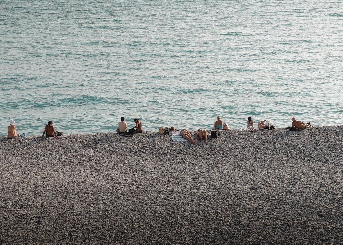 People sunbathing on the famous pebble beach of Nice with blue Mediterranean water