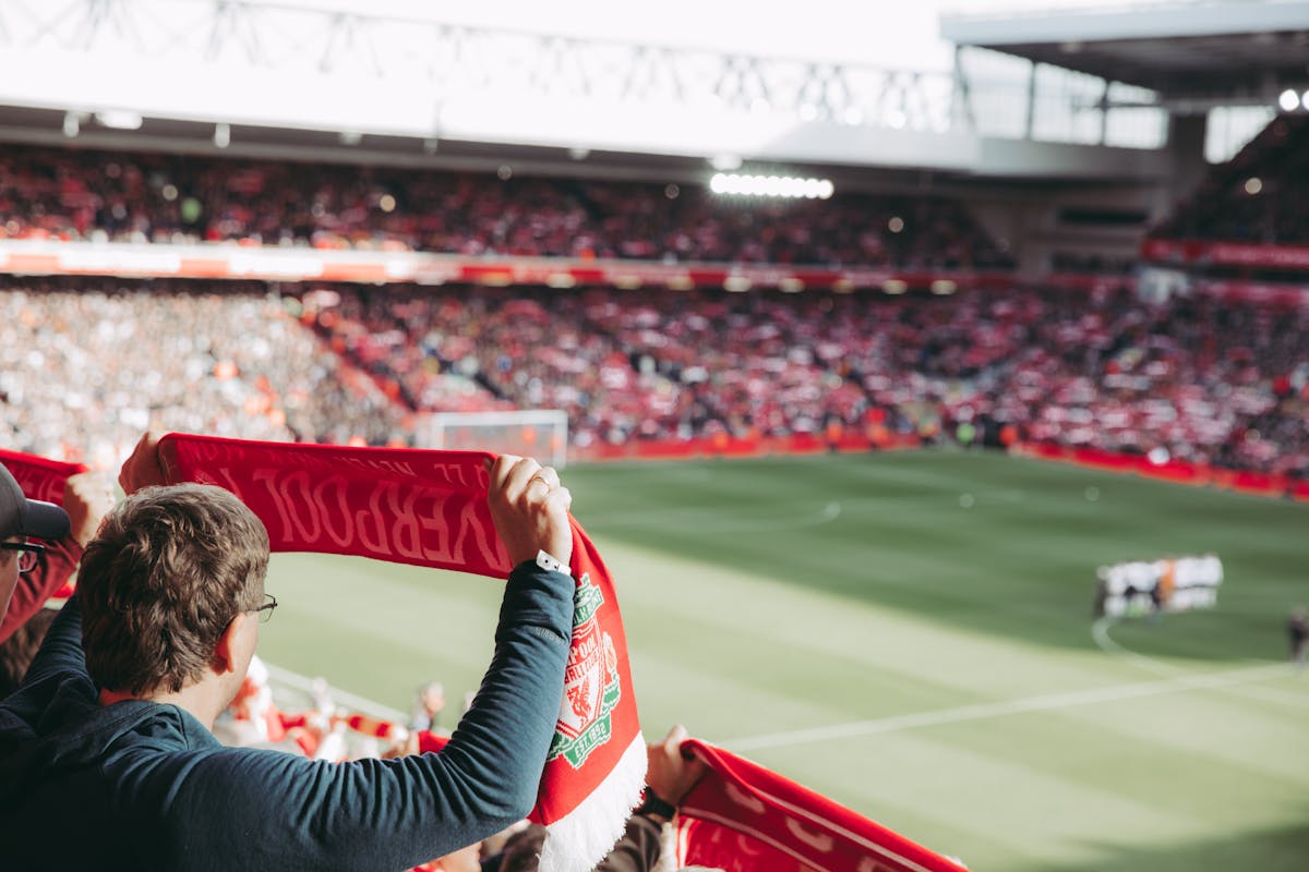 Liverpool FC supporters holding scarves at Anfield Stadium on match day