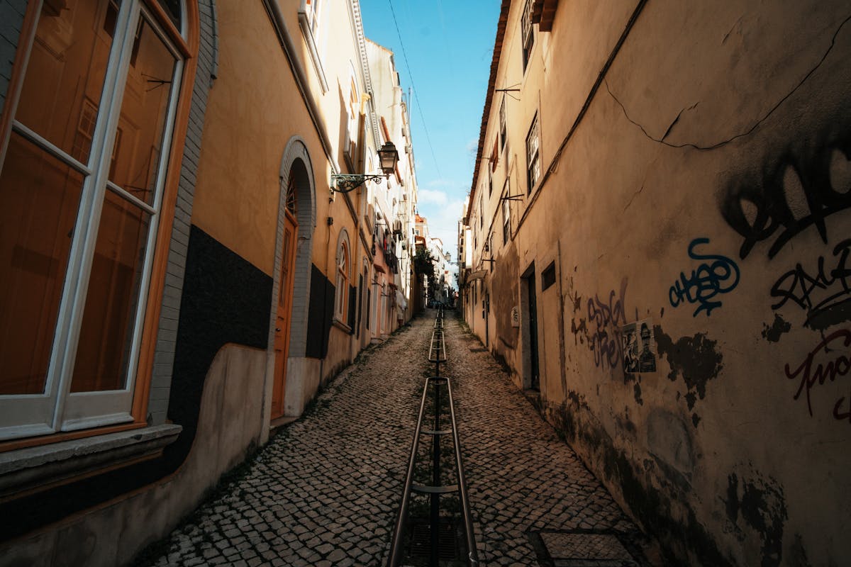 Cobblestone alley with tram tracks and street art in Lisbon