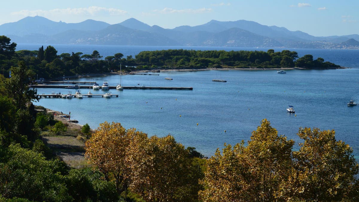 Mediterranean coastline with marina, boats, and green hills in the background