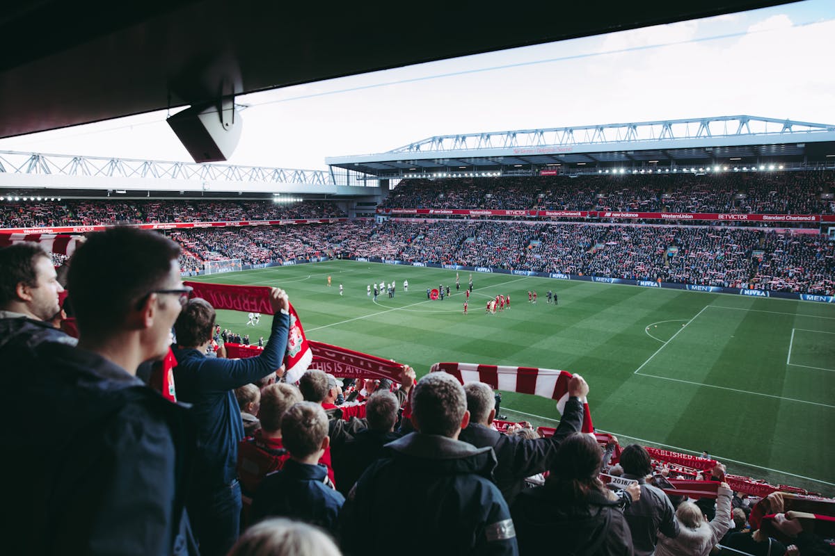 Match day atmosphere at a football stadium with fans cheering under the floodlights