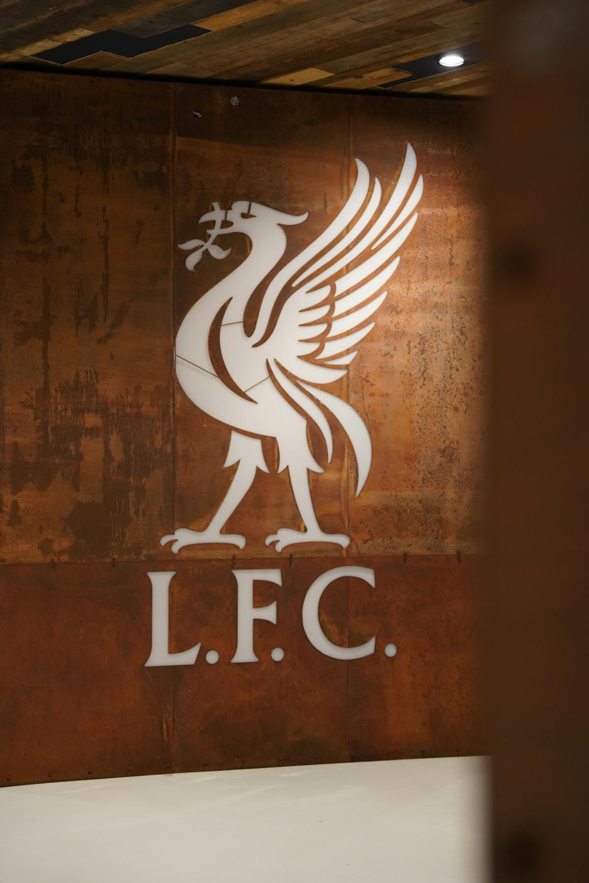 Liverpool FC club crest displayed on a textured wall at Anfield