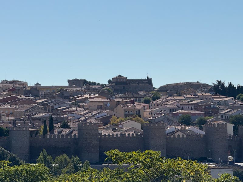 Panoramic view of the medieval walls of Avila stretching across the landscape under a clear blue sky