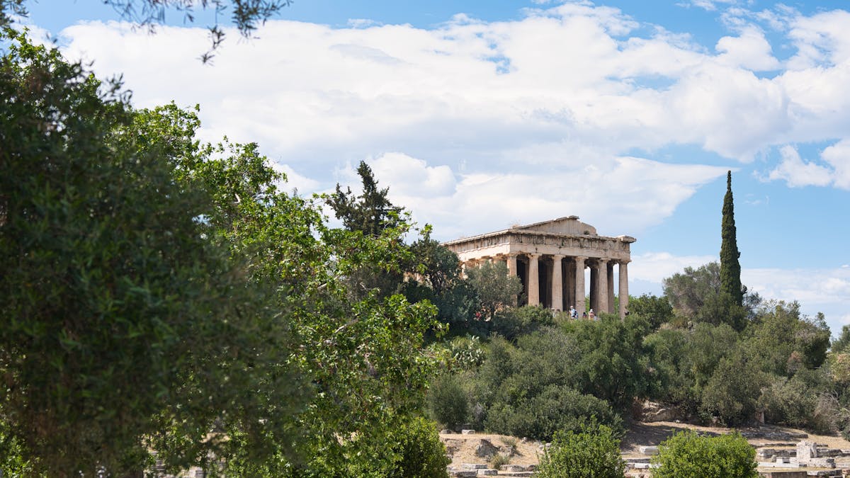 Temple of Hephaestus in Athens surrounded by trees and blue sky