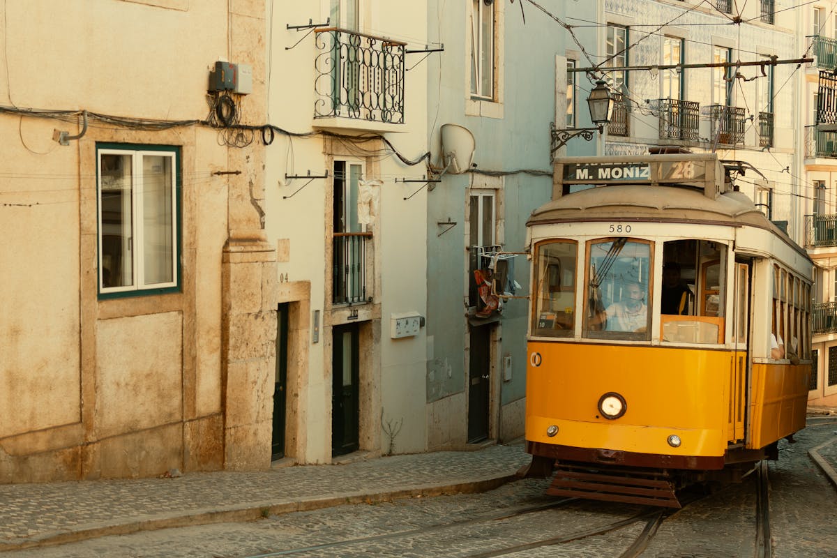A traditional yellow tram winding through narrow cobblestone streets in Lisbon