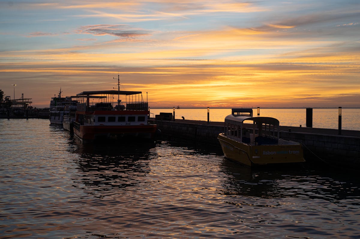 Golden sunset reflecting on the Tagus River in Lisbon with boats in the harbor