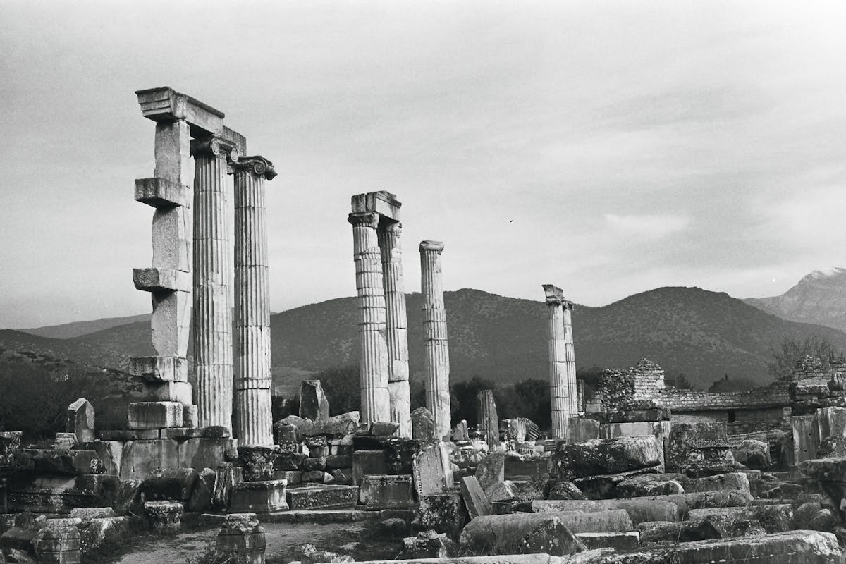 Ancient Greek temple ruins with columns against a mountain backdrop