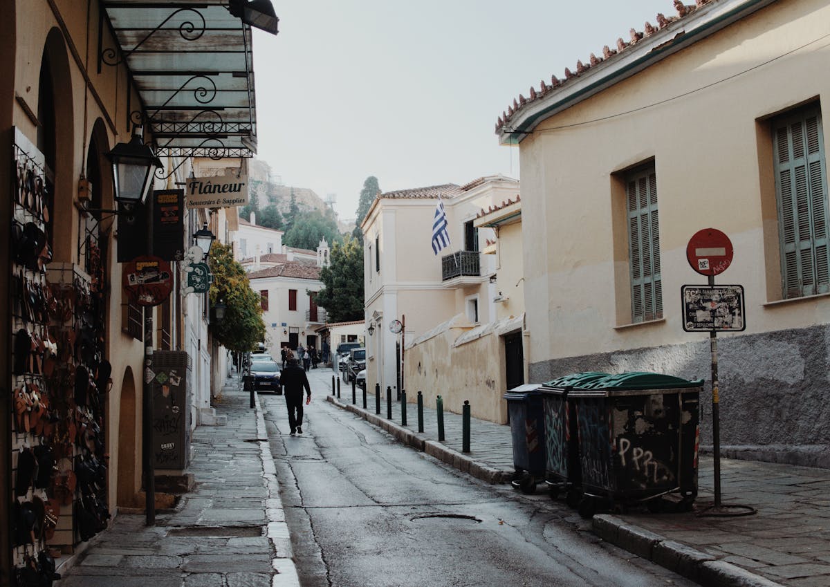 A quiet cobblestone street in the Plaka district of Athens with Greek flag