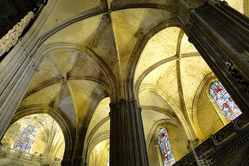 The soaring Gothic interior of Seville Cathedral with massive stone columns and vaulted ceiling