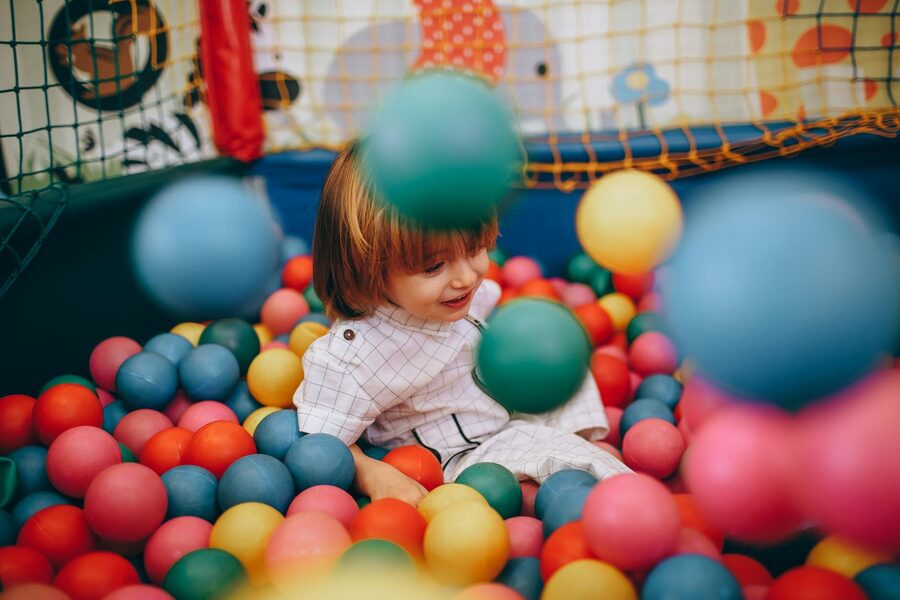 A cheerful child playing and laughing in a colorful indoor ball pit