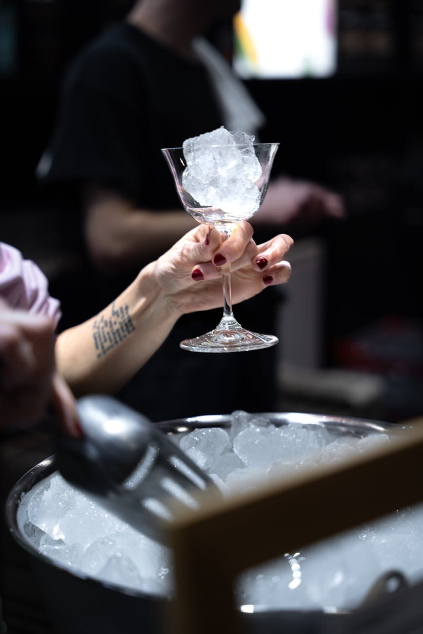 Hand holding a cocktail glass with ice cubes