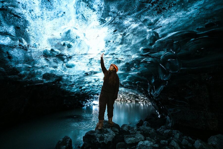 A spellbinding view of a person exploring the vivid blue ice caves in Iceland.